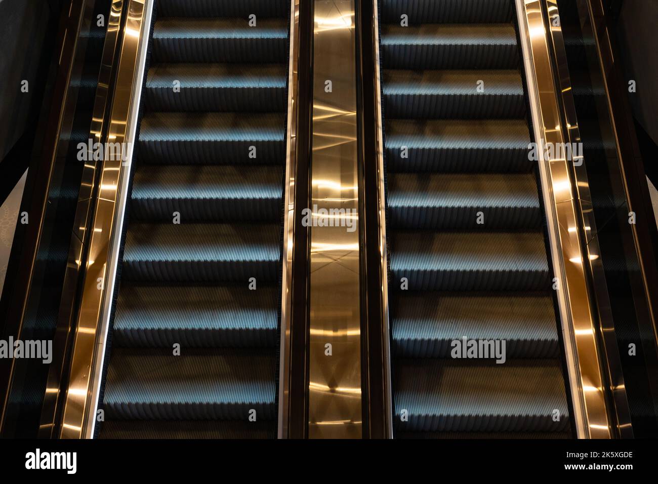 Escalators in the modern building. Golden and gray colored escalators ...