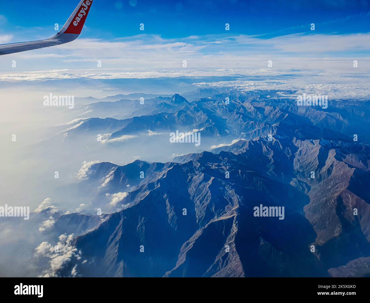 The Alps from the plane with a scattering of snow and cloud Stock Photo ...