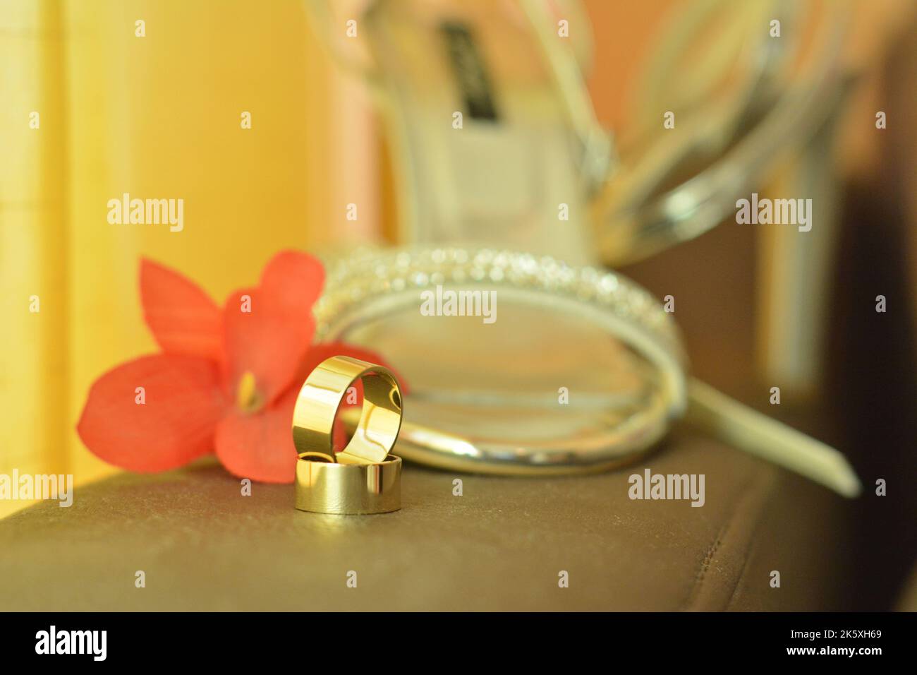 A closeup shot of a pair of golden wedding rings with blurred shoes on ...