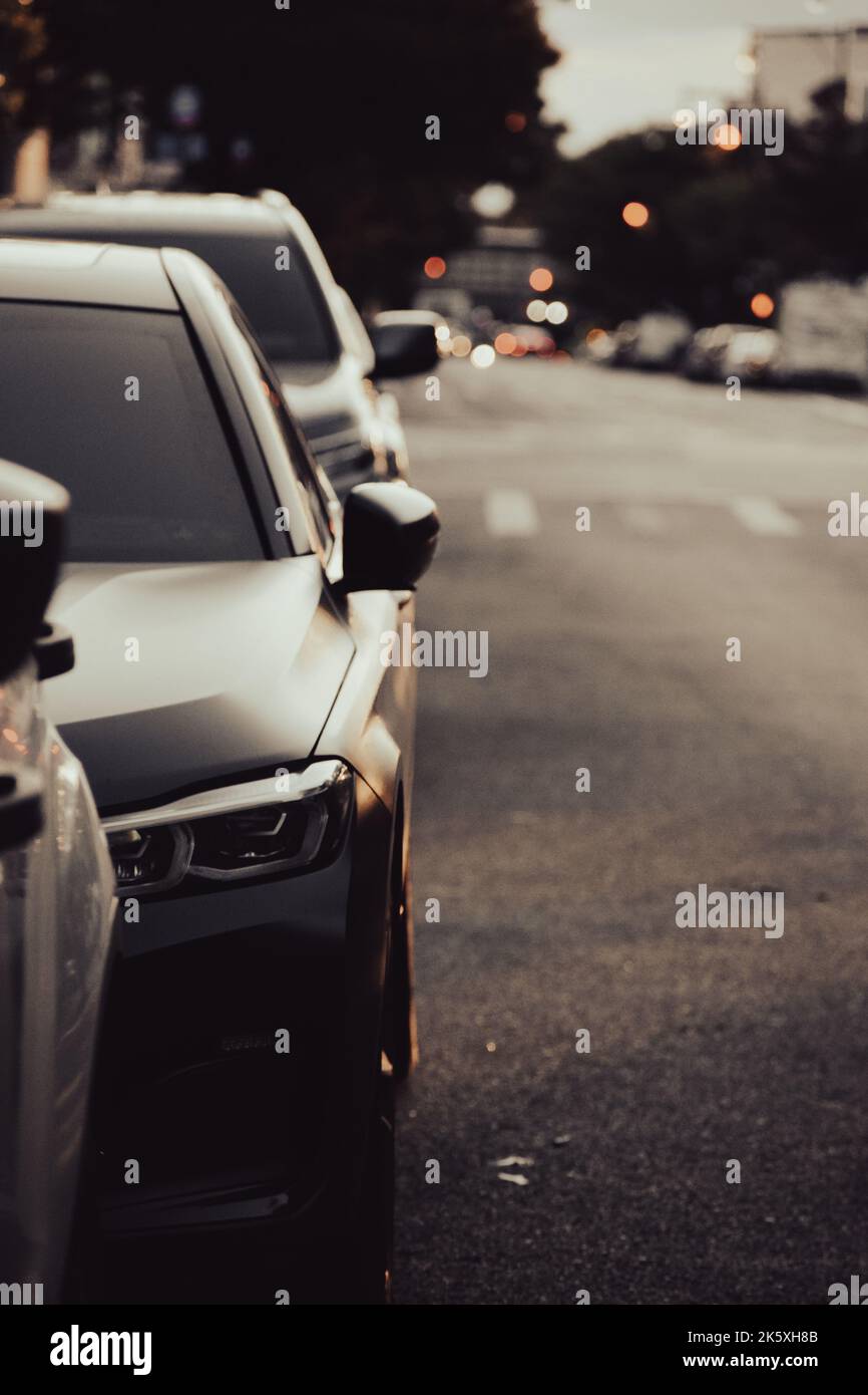 A vertical shot of cars parked on the street with bokeh lights in the ...