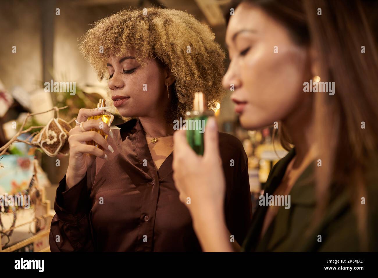 Two beautiful women smelling perfume during shopping at store Stock ...