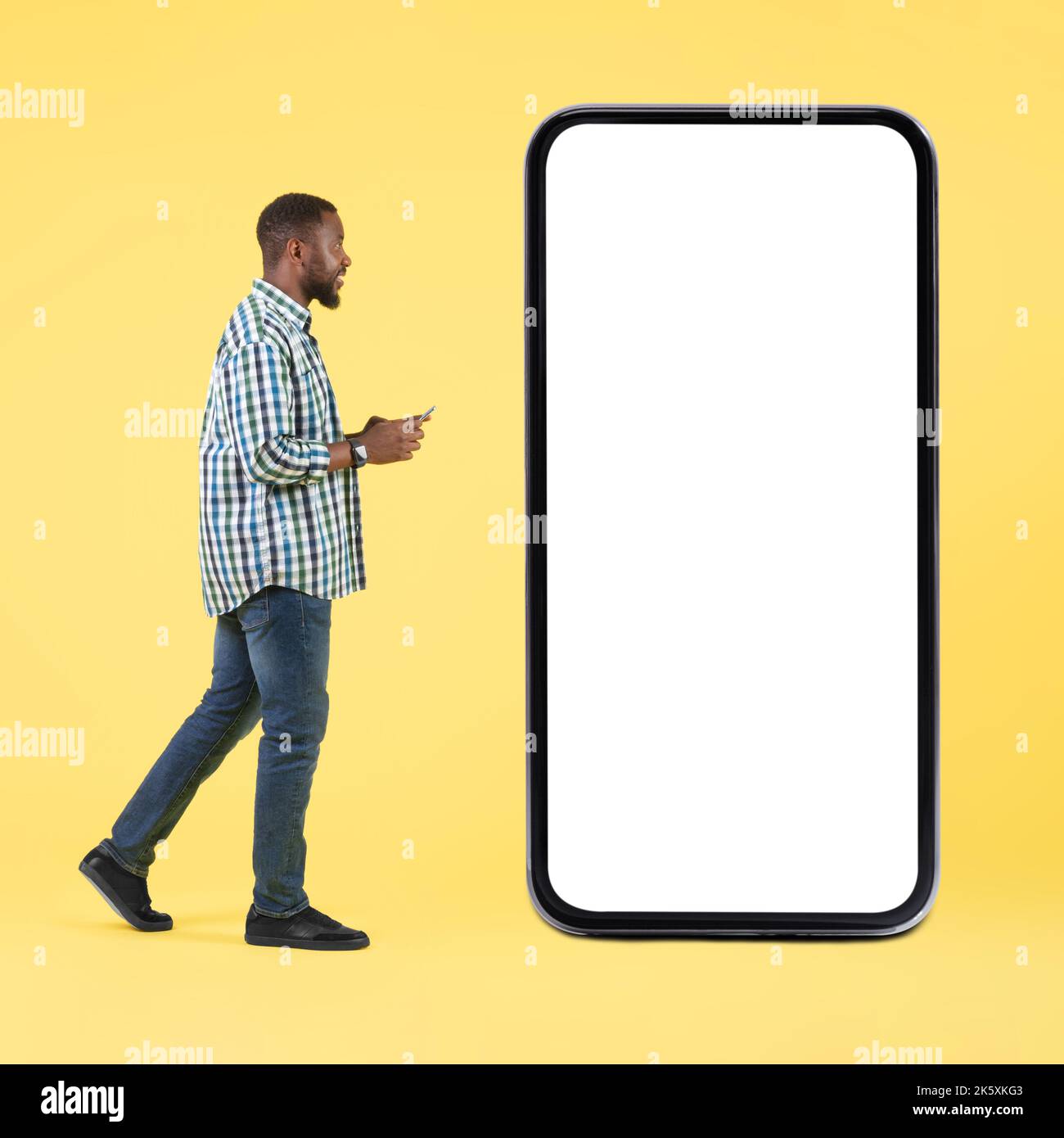 Black Man Using Phone Walking Near Huge Smartphone Screen, Studio Stock ...