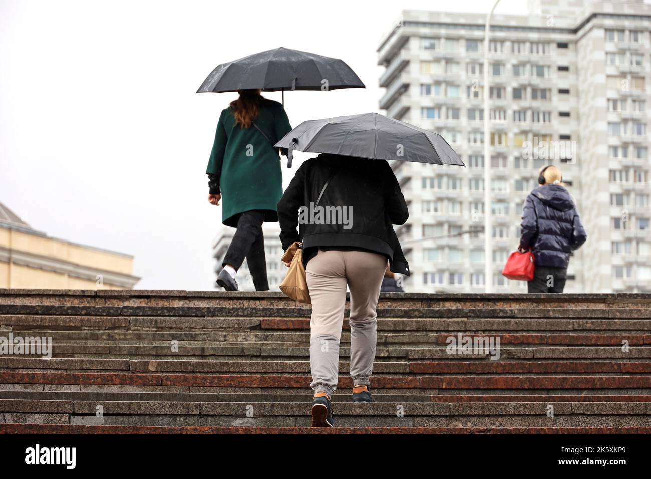 People with umbrellas walking up the steps on city buildings background ...