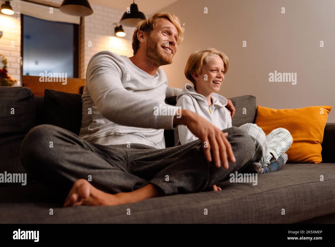 Ginger father and son laughing together while resting on couch at home ...