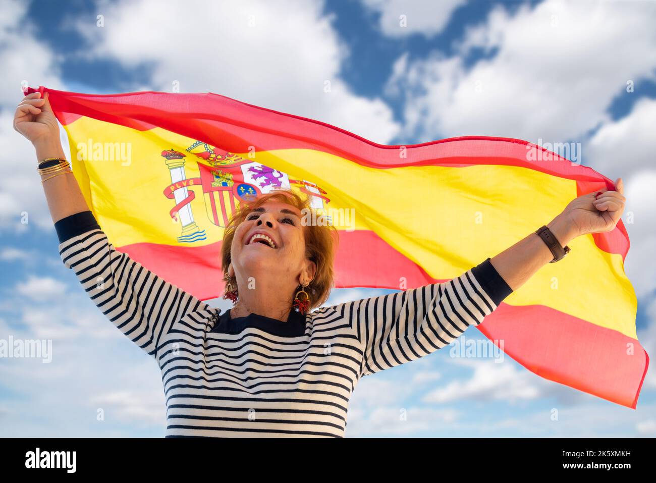 Older lady proud to be Spanish smiling and waving the Spanish flag ...