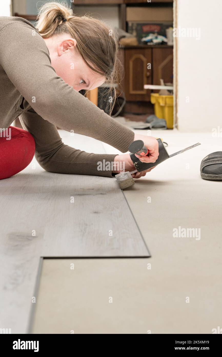 Woman installs quartz vinyl floor, installation on a flat surface ...