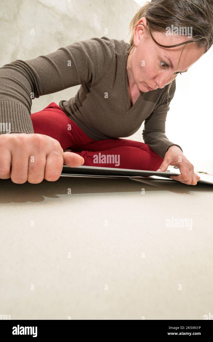 Woman installs quartz vinyl flooring at home, exhausted woman from work ...