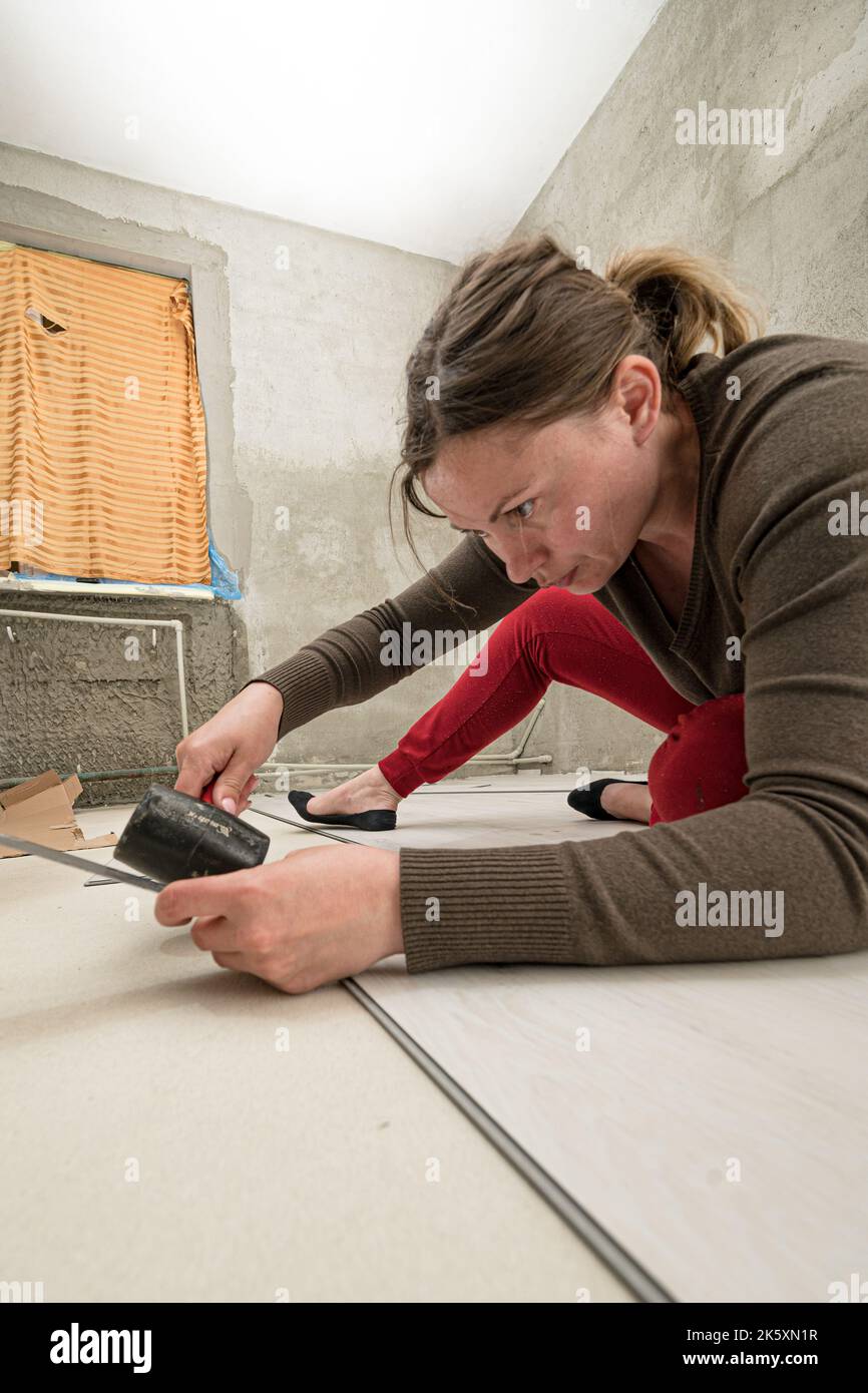 Woman installs quartz vinyl flooring at home, exhausted woman from work ...
