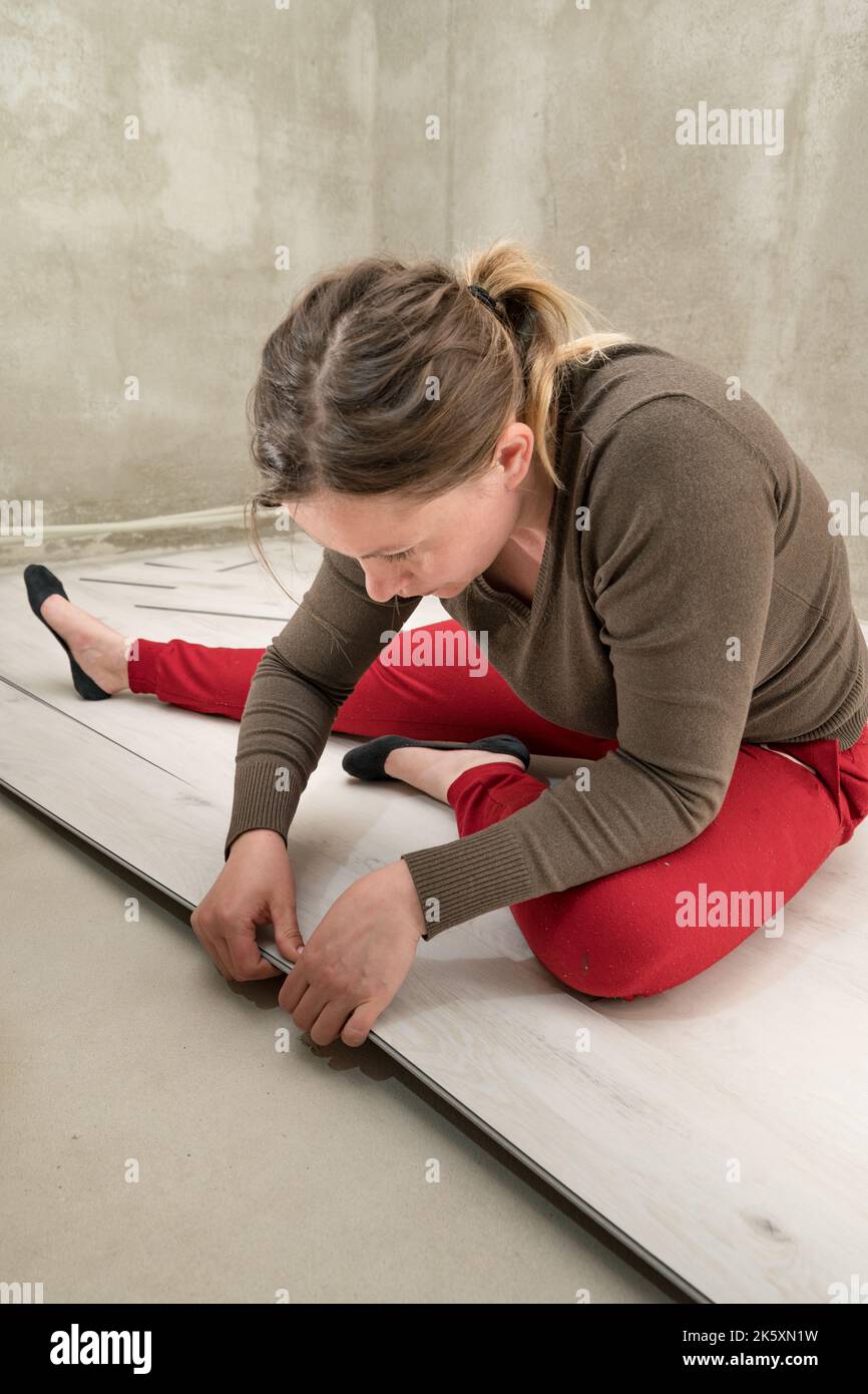 Woman installs quartz vinyl flooring at home, exhausted woman from work ...