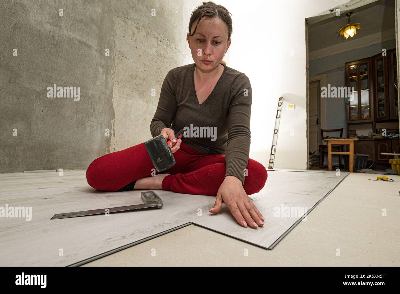 Installing a quartz vinyl floor, a woman performs installation work ...