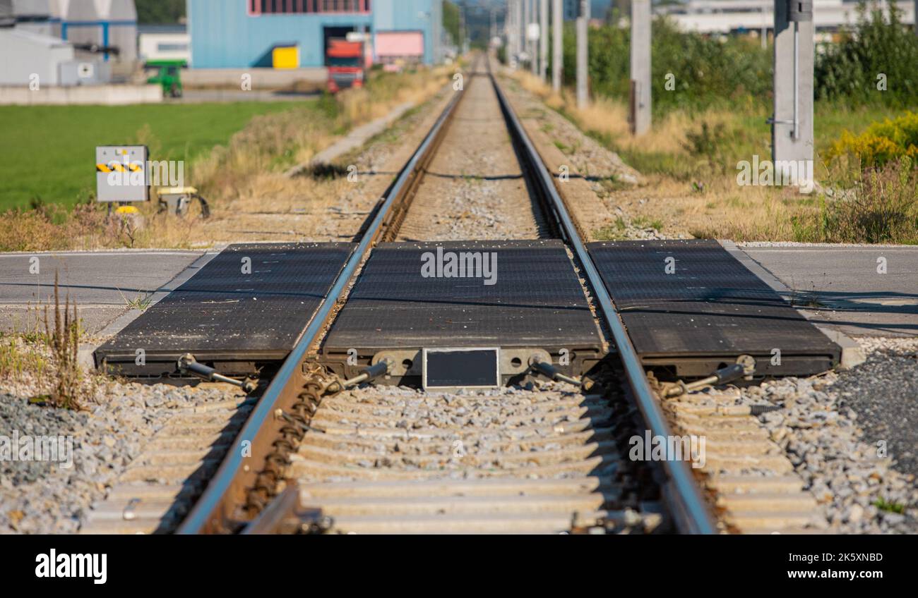 Railway crossing viewed from the rails, asphalt road crossing railway line using rubber elements ...