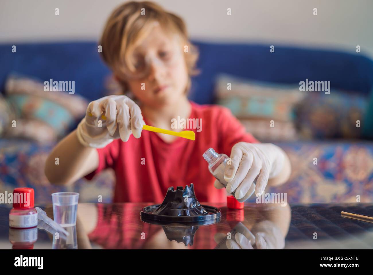 Kid boy doing chemical experiment at home. Child with protective glasses study using pipette ...