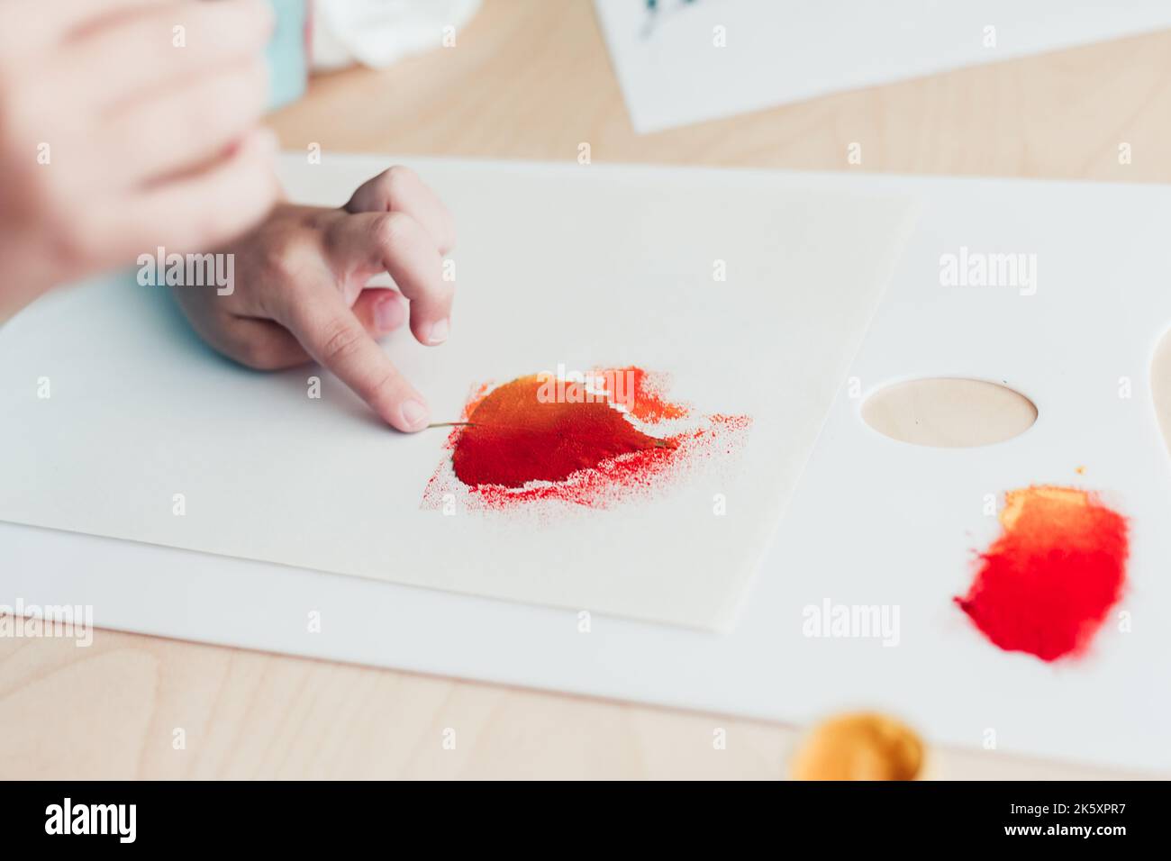 Cute child sitting at desk and making picture from dry birch leaves ...