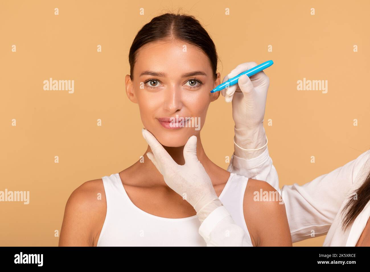 Doctor drawing marks on young woman's face for cosmetic surgery ...