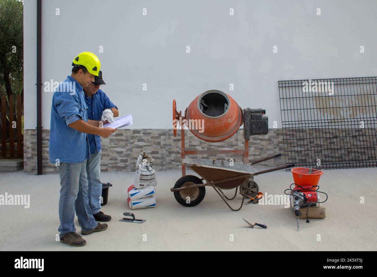 two men an engineer and a construction worker consulting the construction plan. Masonry and ...