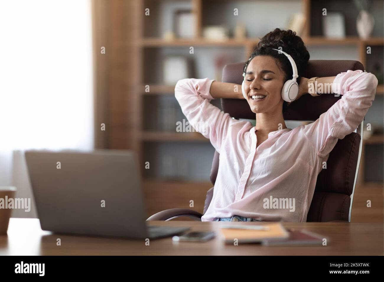 Relaxed young woman listening to music while working online Stock Photo ...