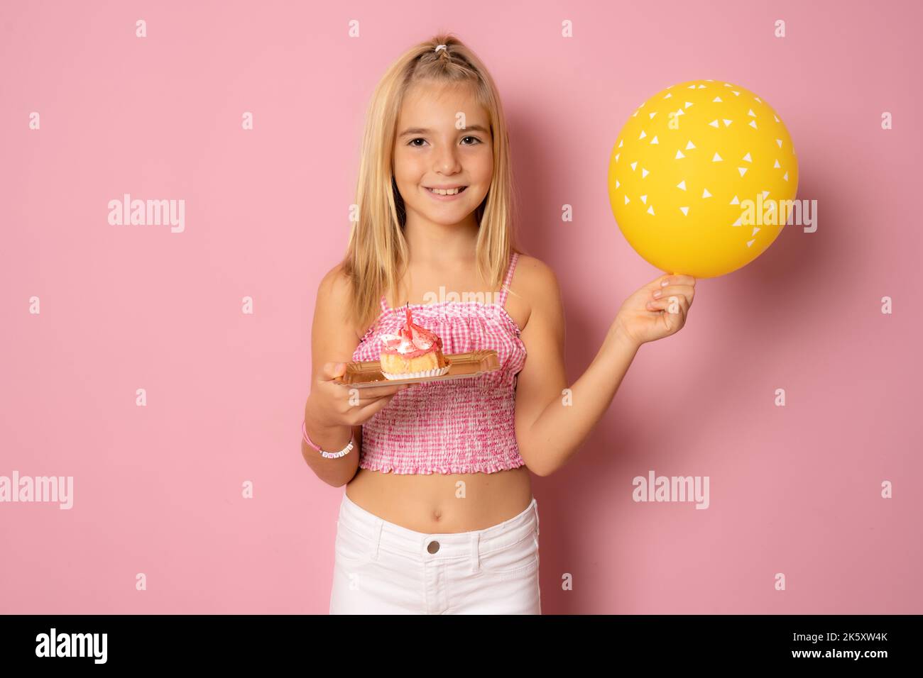Adorable little kid with balloons and cake isolated over pink ...