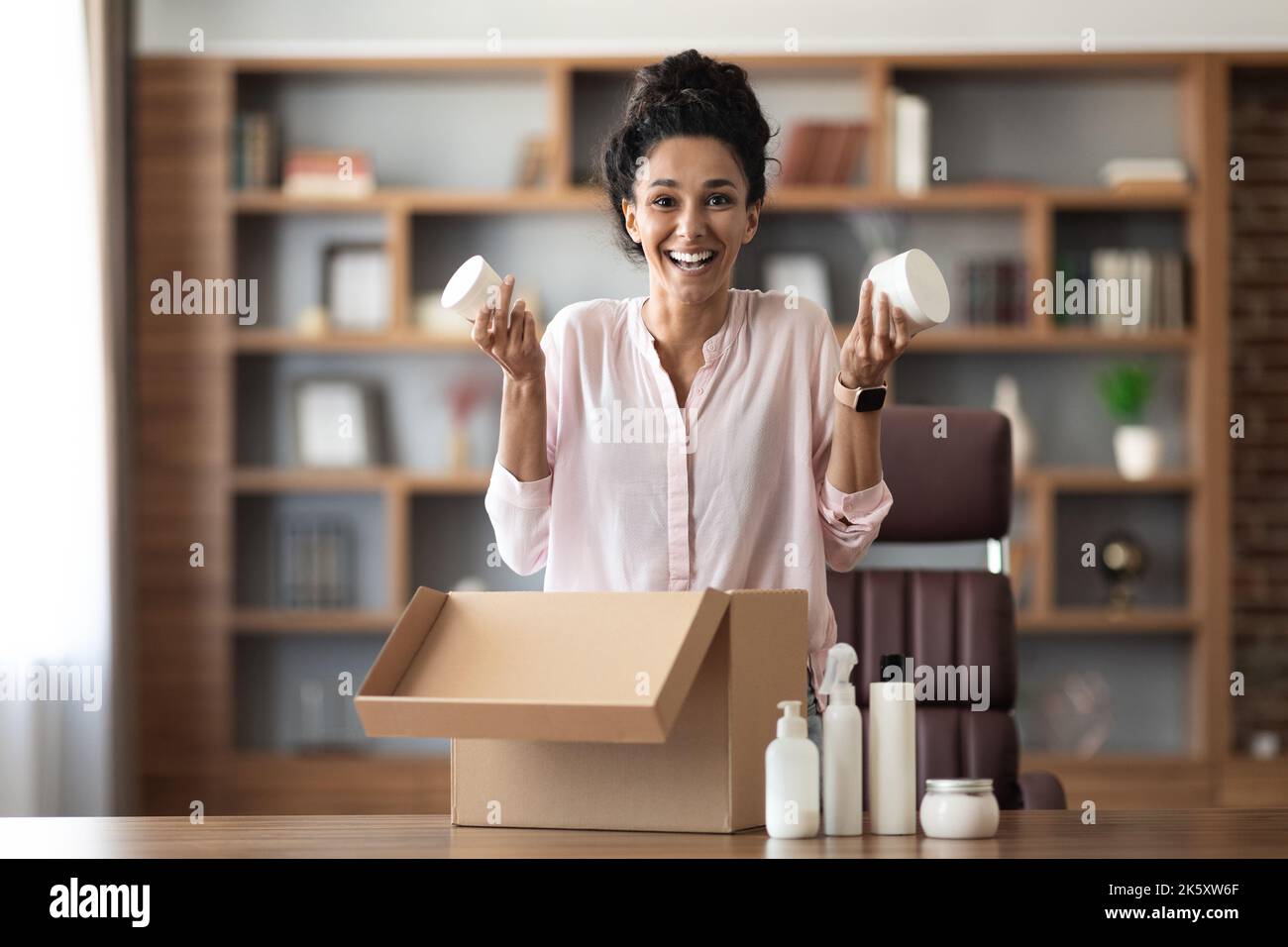 Excited young woman customer checking her parcel with cosmetics Stock ...