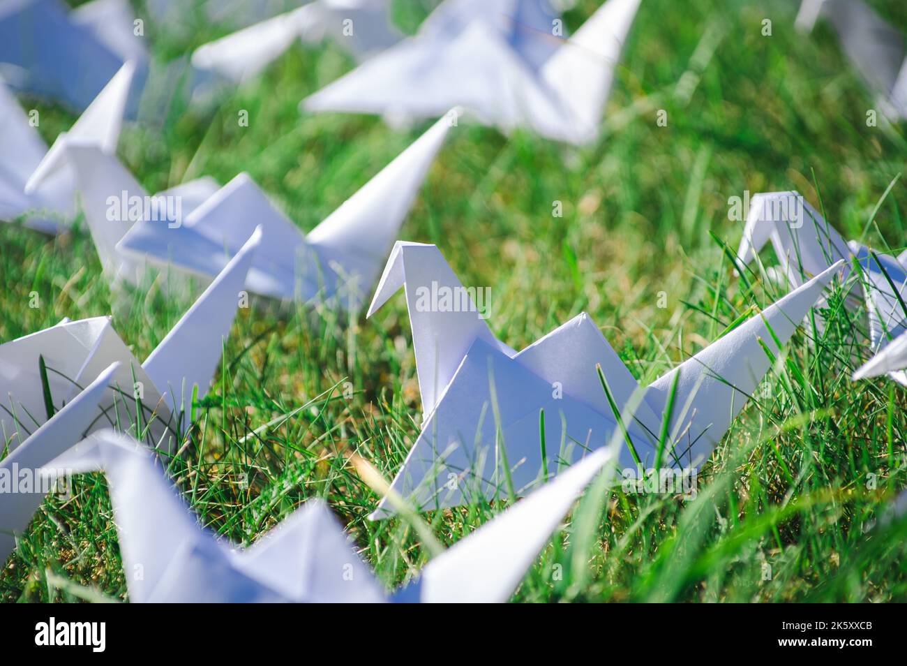 Japanese folded Origami cranes on fresh grass. Hundreds handmade paper ...