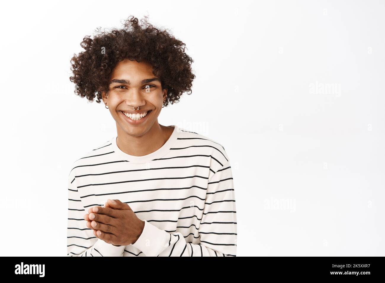 Close up portrait of smiling young man holding hands together, namaste ...