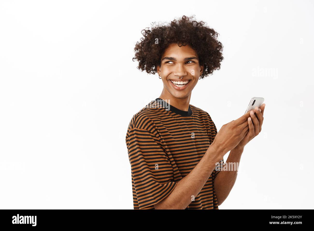 Portrait of young modern guy using mobile phone, looking behind his ...