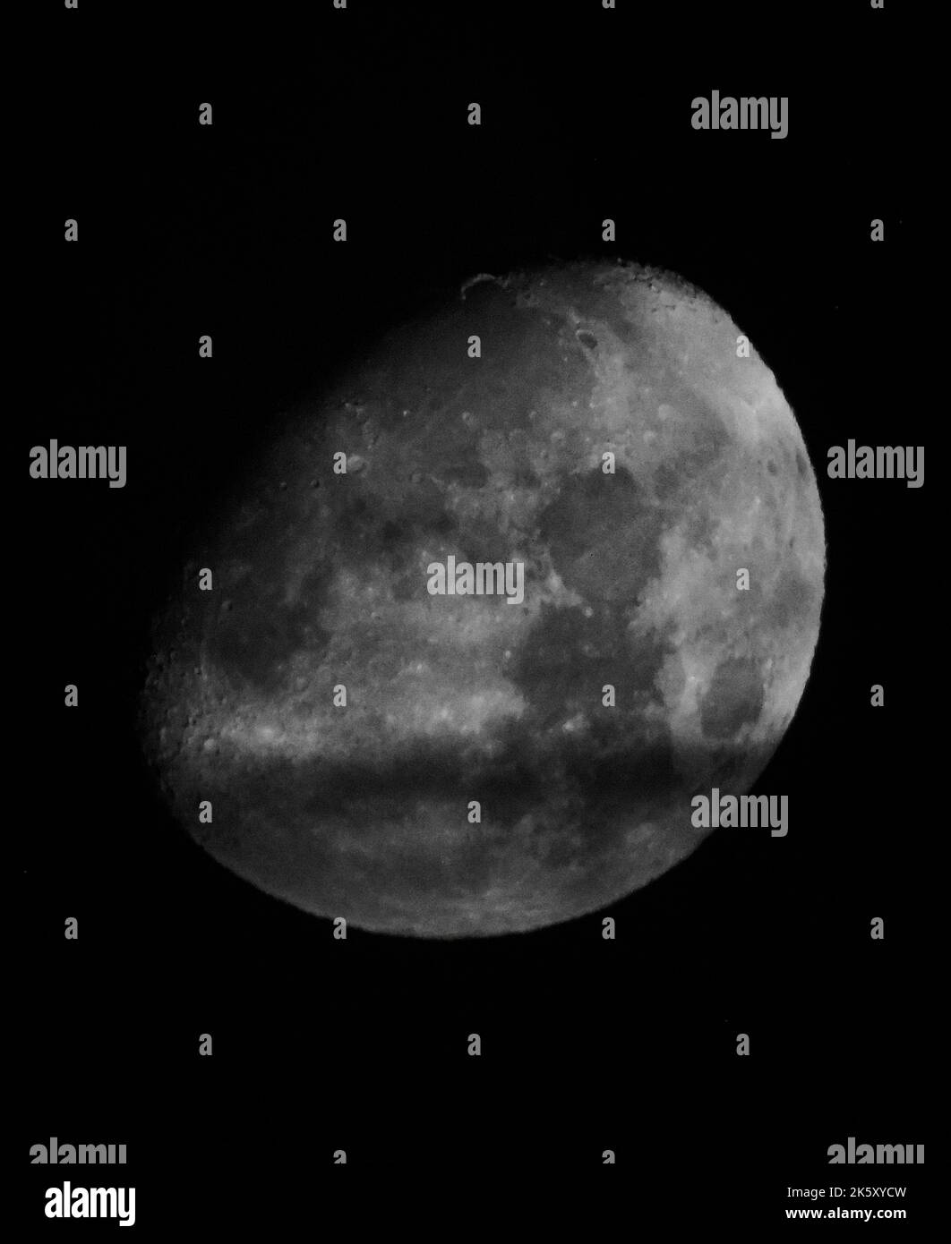 A vertical closeup of the gray moon with details isolated on black ...