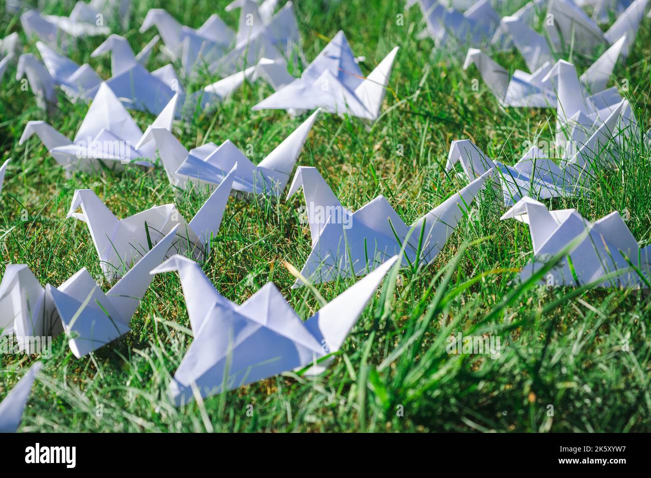 Japanese folded Origami cranes on fresh grass. Hundreds handmade paper ...