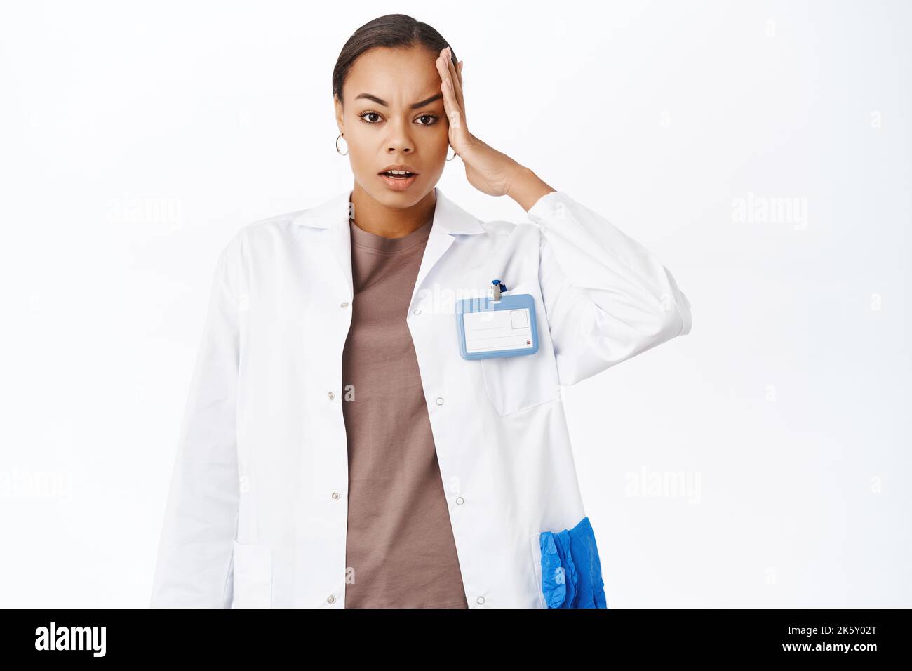 Troubled female doctor, holds hand on head, look concerned and ...