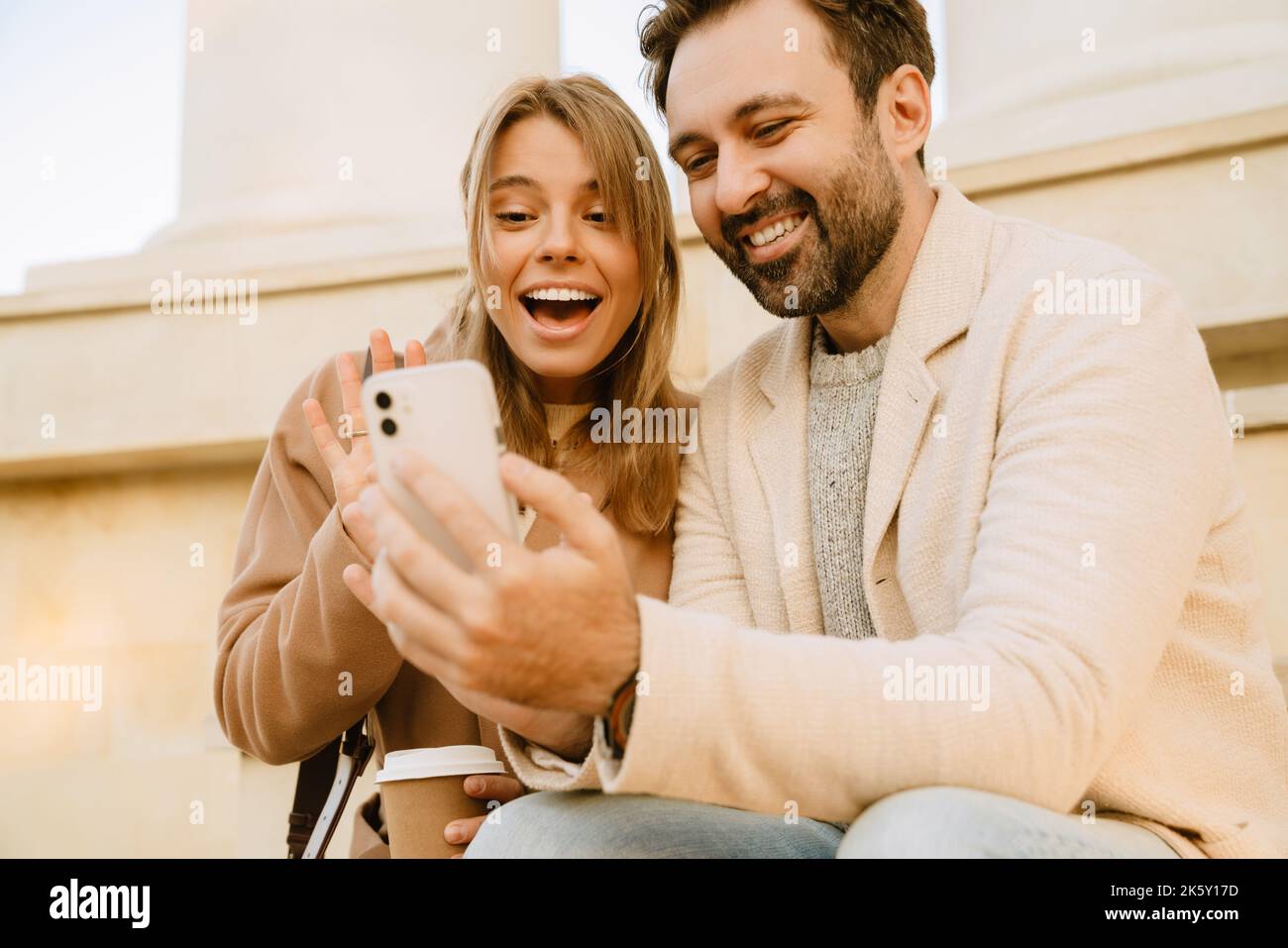 White romantic couple using cellphone and laughing during date outdoors ...