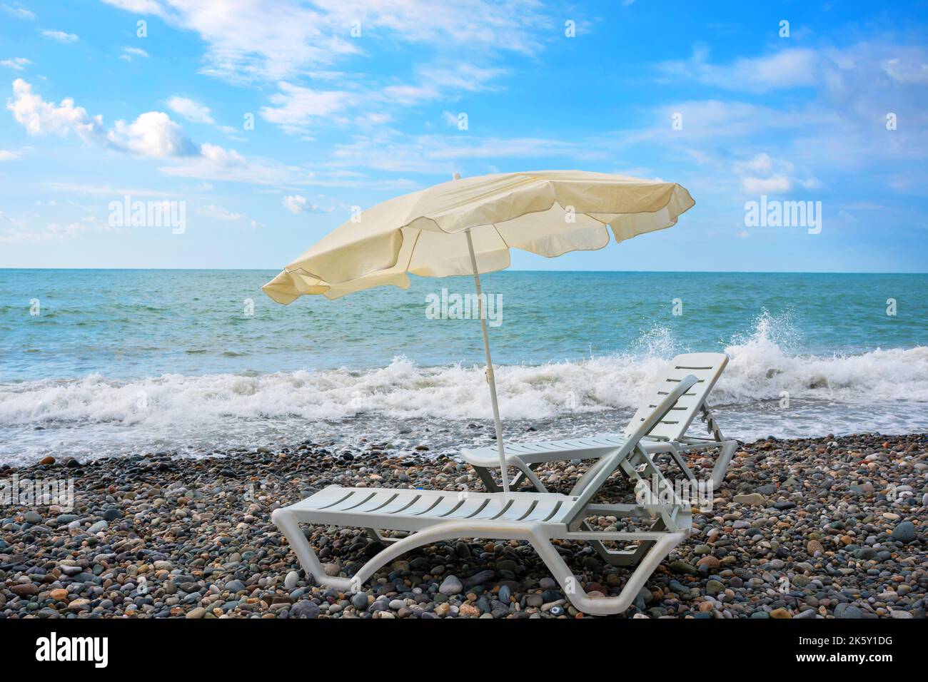 Two chaise lounges and a sunshade on the sea beach Stock Photo - Alamy