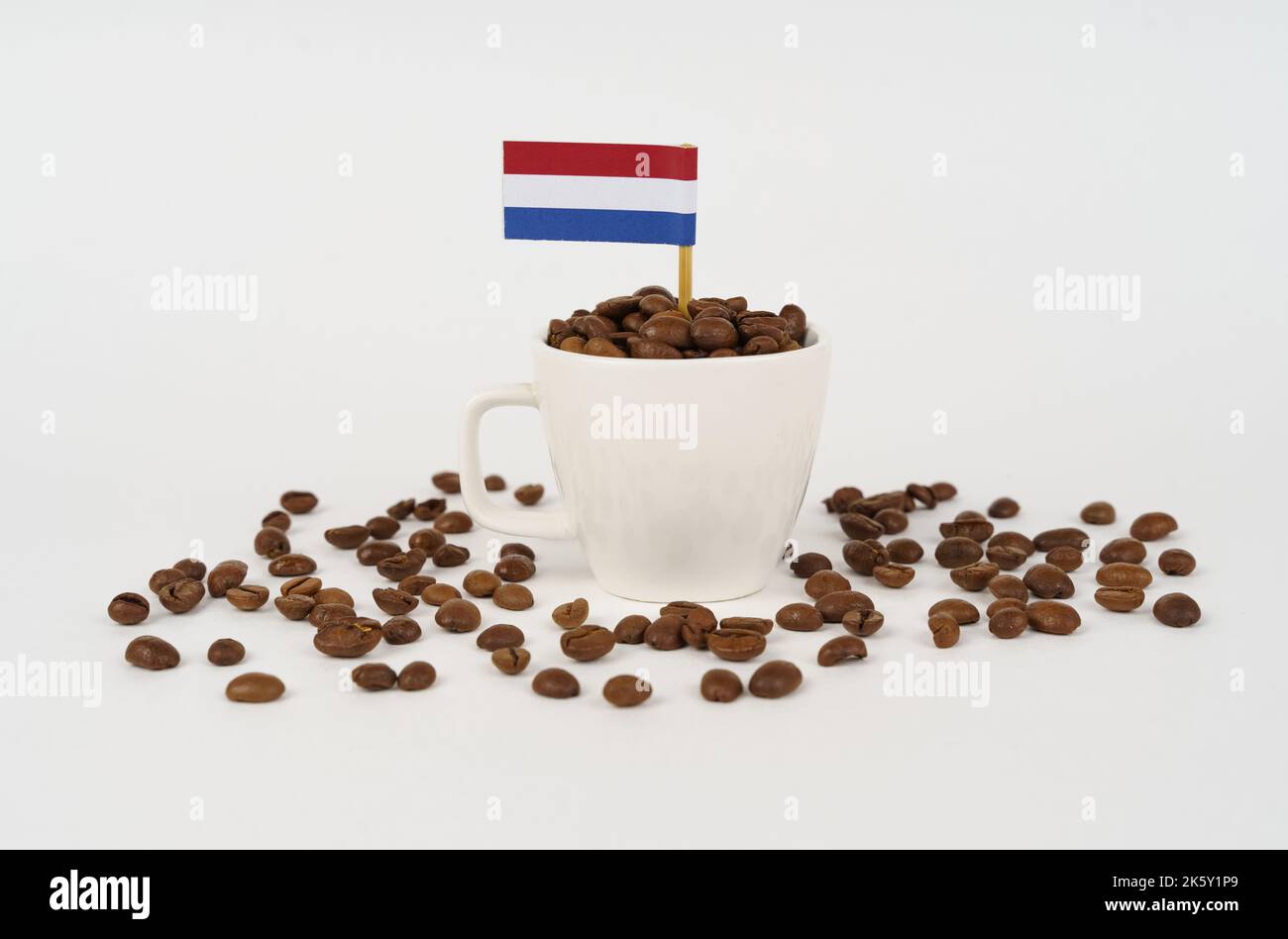 The flag of the Netherlands sticks out of a cup of roasted coffee beans ...