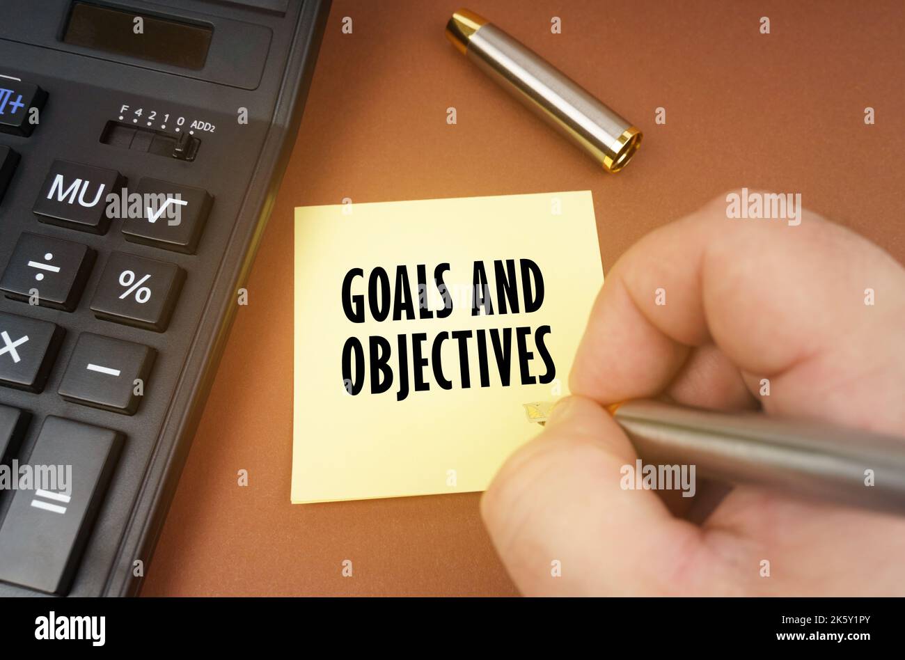 Business concept. A calculator lies on a brown surface, a hand with a ...