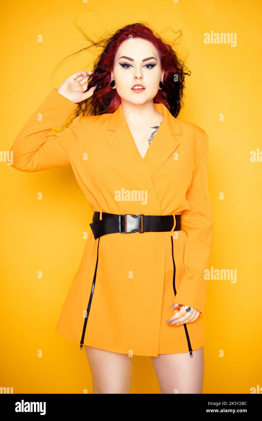 Gorgeous model on an orange background with curly hair. Fashion girl in ...