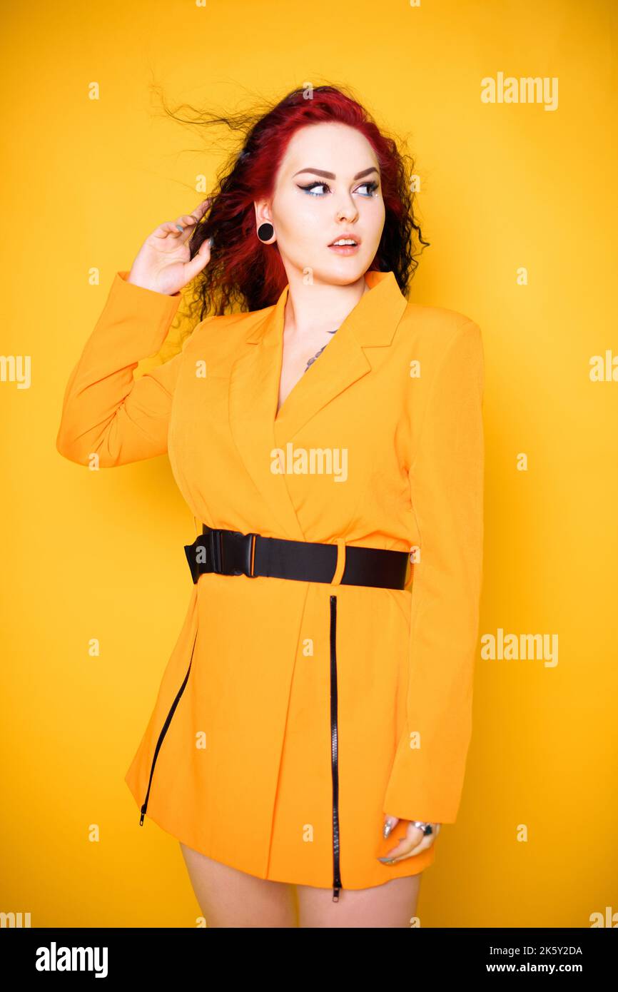 Gorgeous model on an orange background with curly hair. Fashion girl in ...