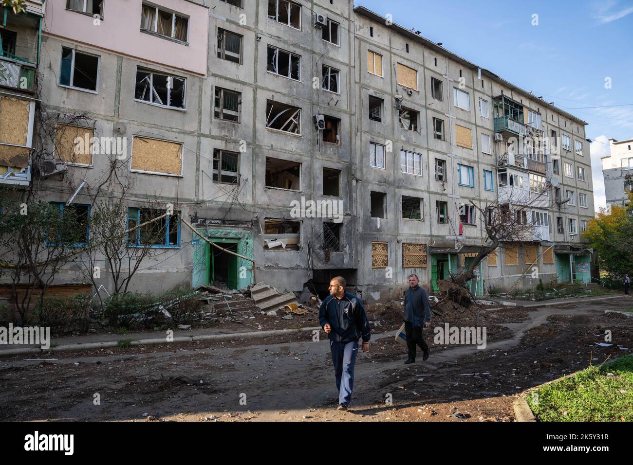 Bakhmut, Ukraine. 04th Oct, 2022. Two men walk in front of an apartment ...