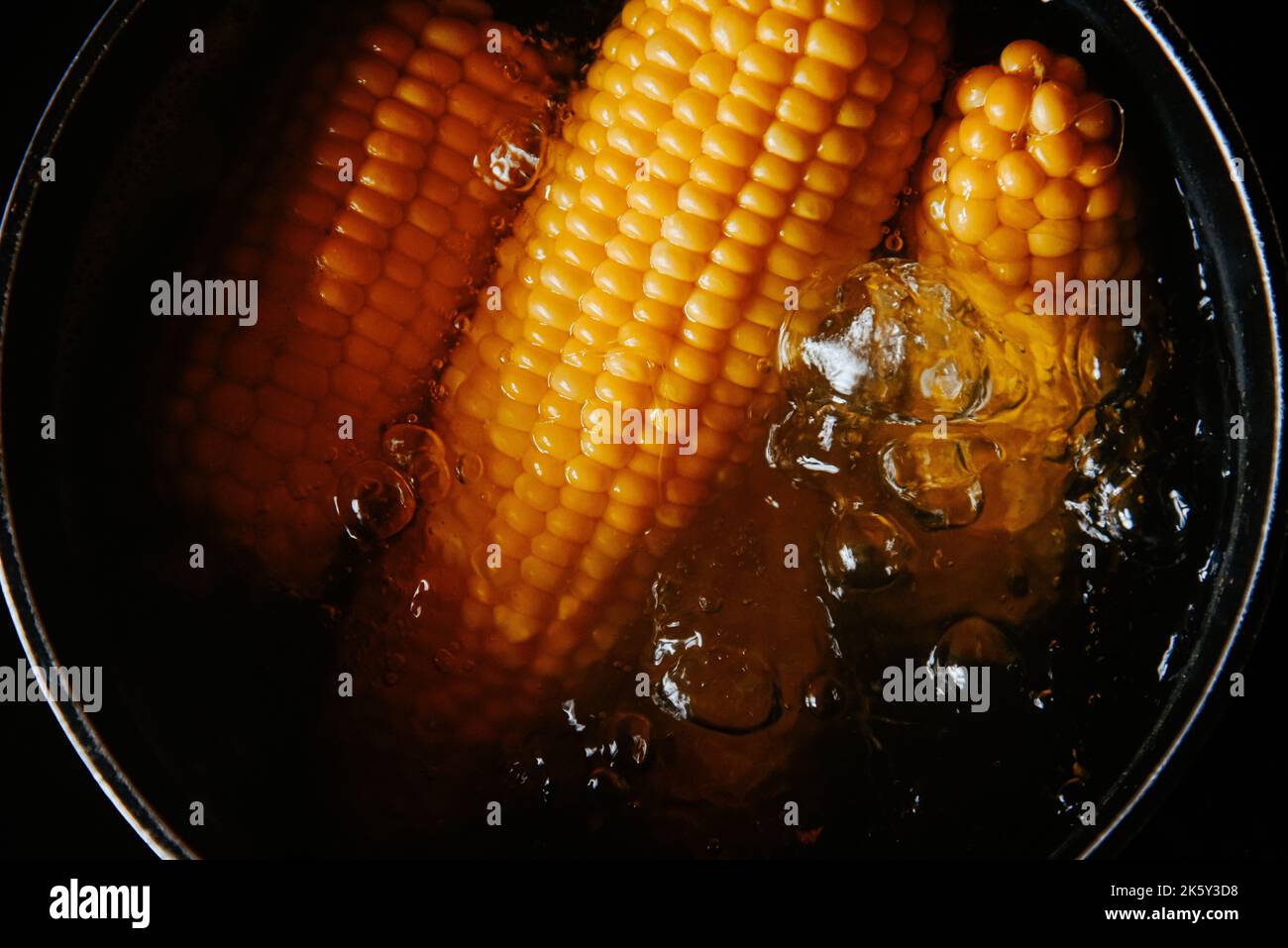 Orange juicy corn is boiled in water with salt. Corn in boiling water ...