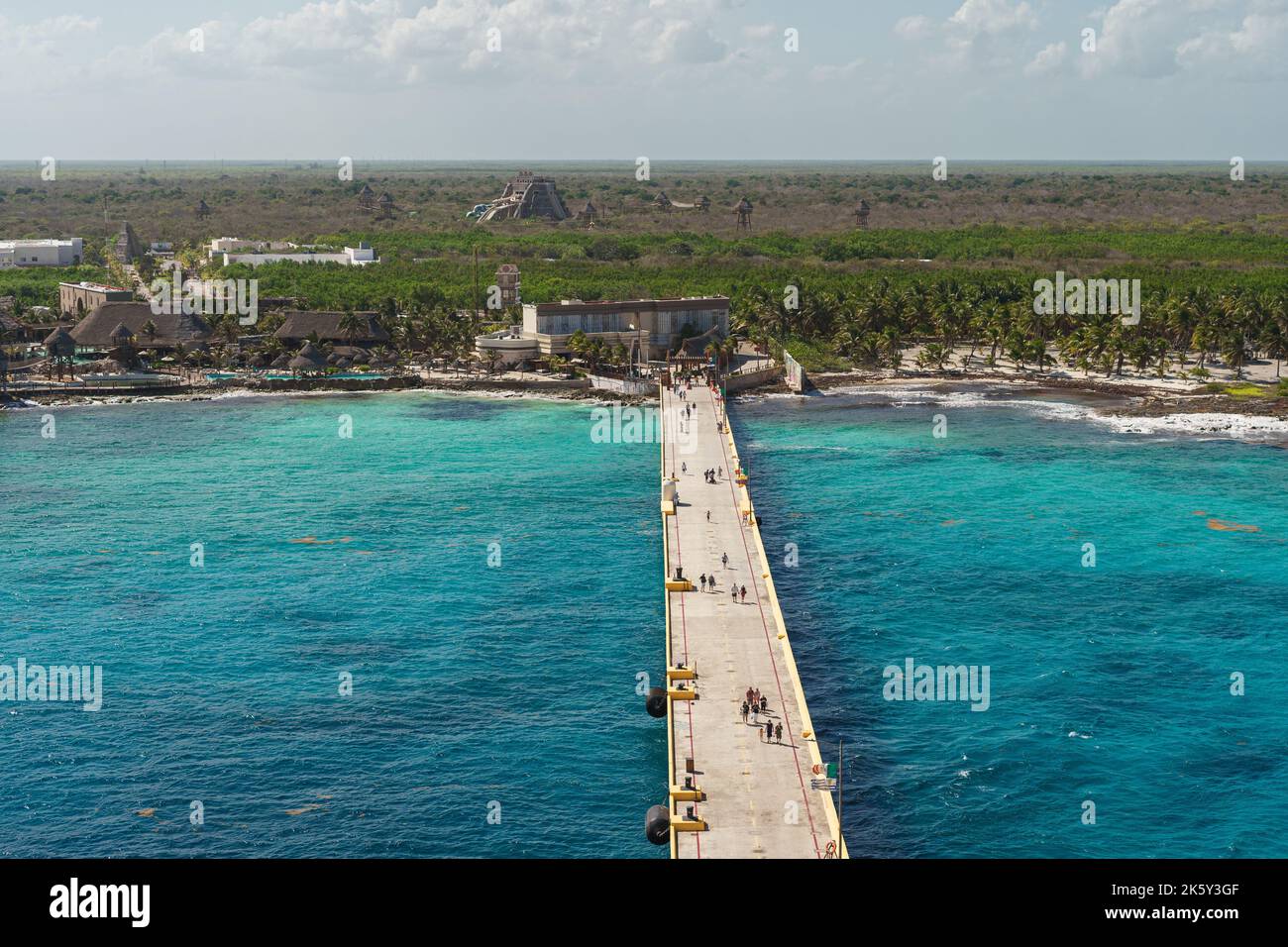 An aerial view of a bridge over a clear ocean with trees on the coast ...