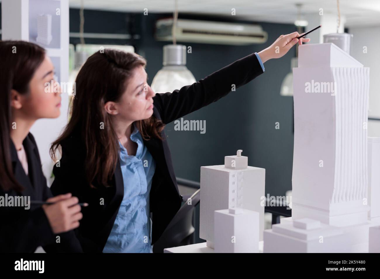 Real estate agency employees coworking, discussing building 3d model ...