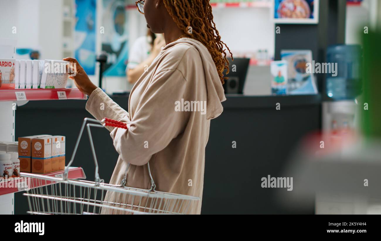 African american woman shopping medicaments and vitamins from shelves ...