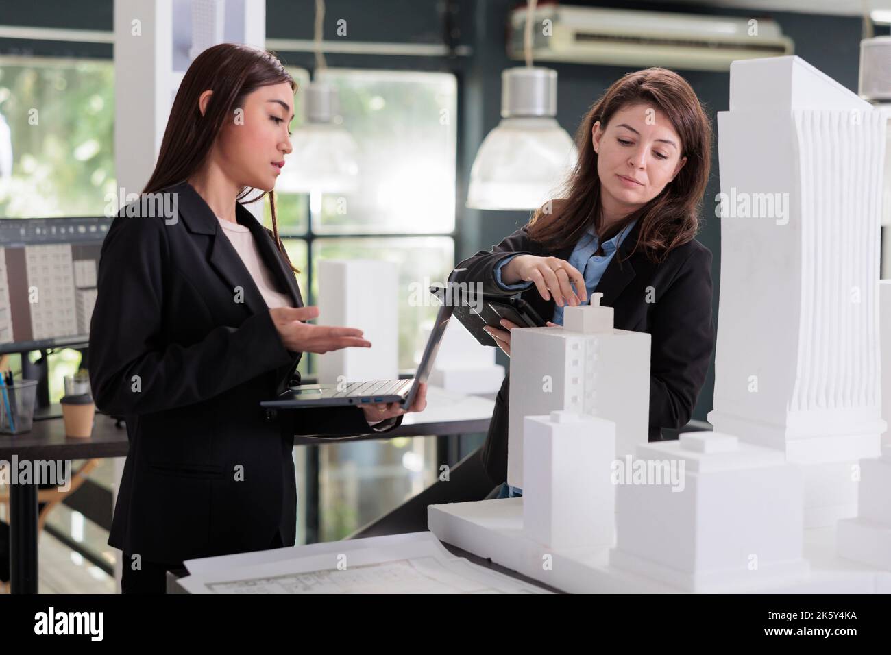 Architects discussing 3d apartment building model, engineers holding laptop, working on ...