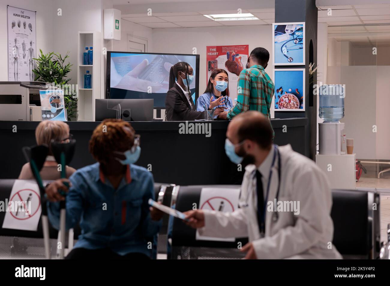 Female hospital staff members attending a sick young african american ...