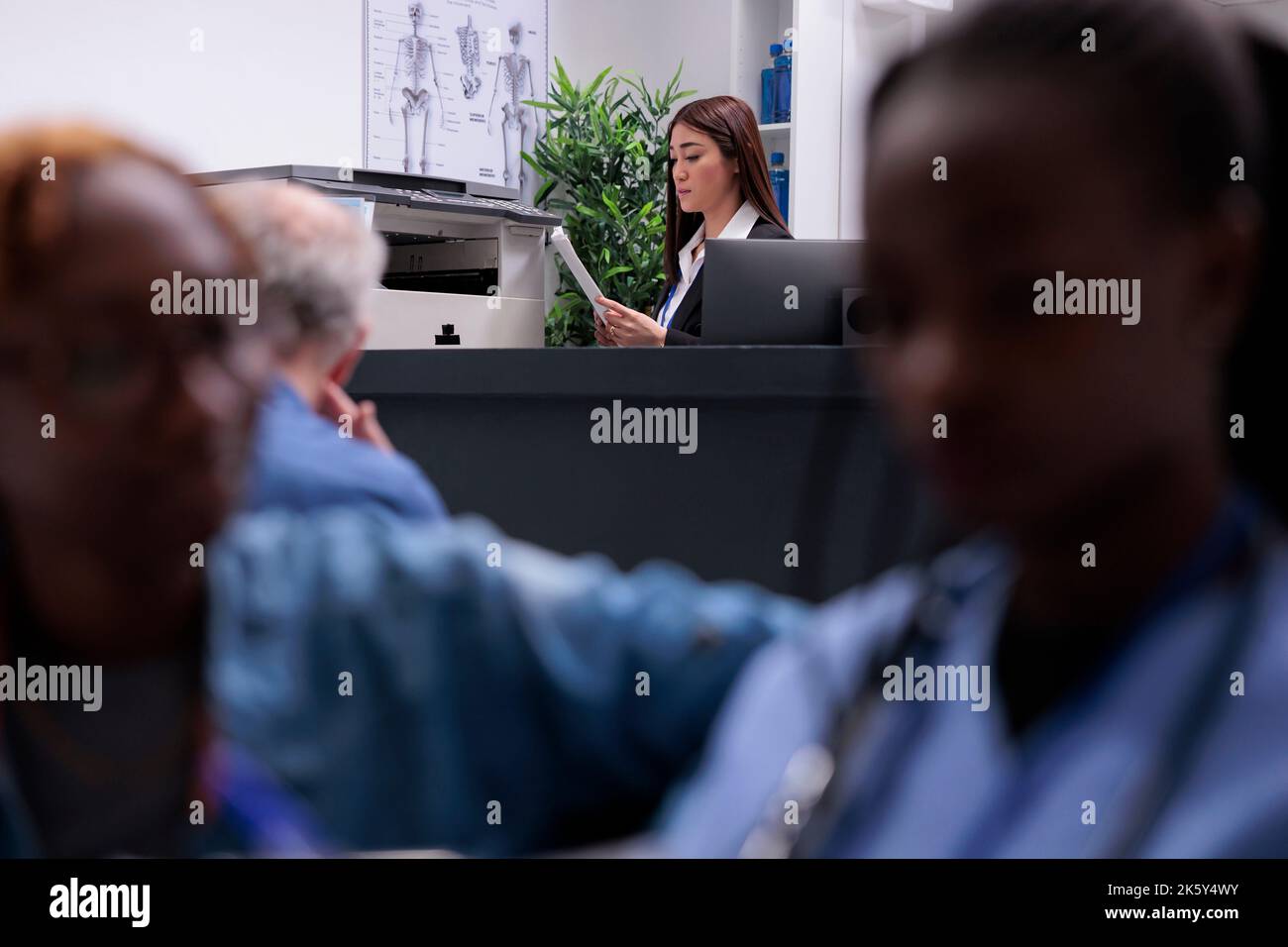 Asian receptionist using medical report papers to help patients with ...