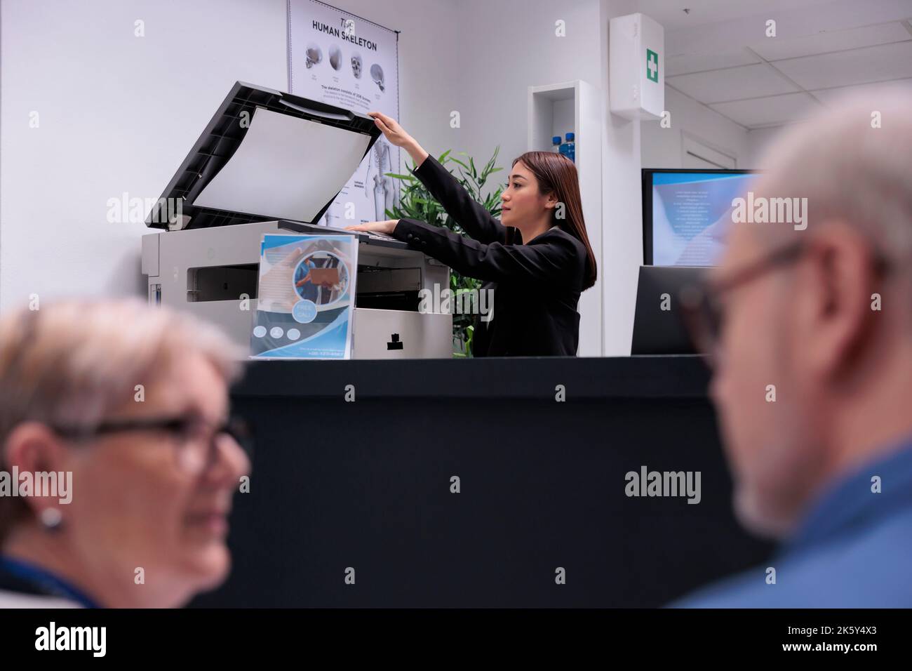 Secretary using copy printer at reception counter to make report papers ...