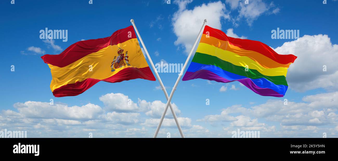 two crossed flags LGBT Pride and spain waving in wind at cloudy sky ...