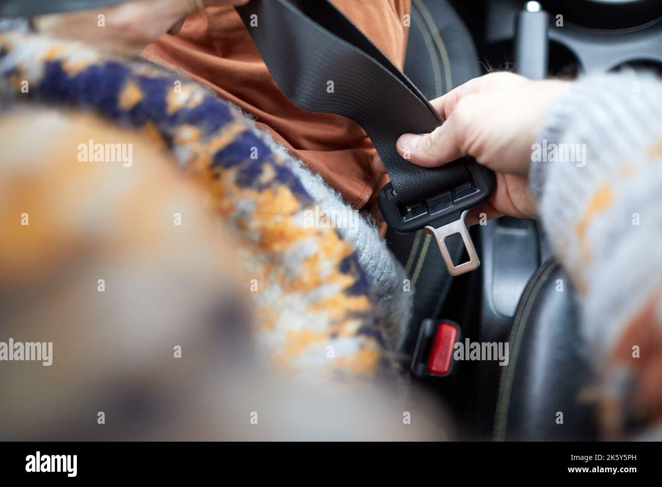 Close up of unrecognizable person fastening seatbelt while driving car ...