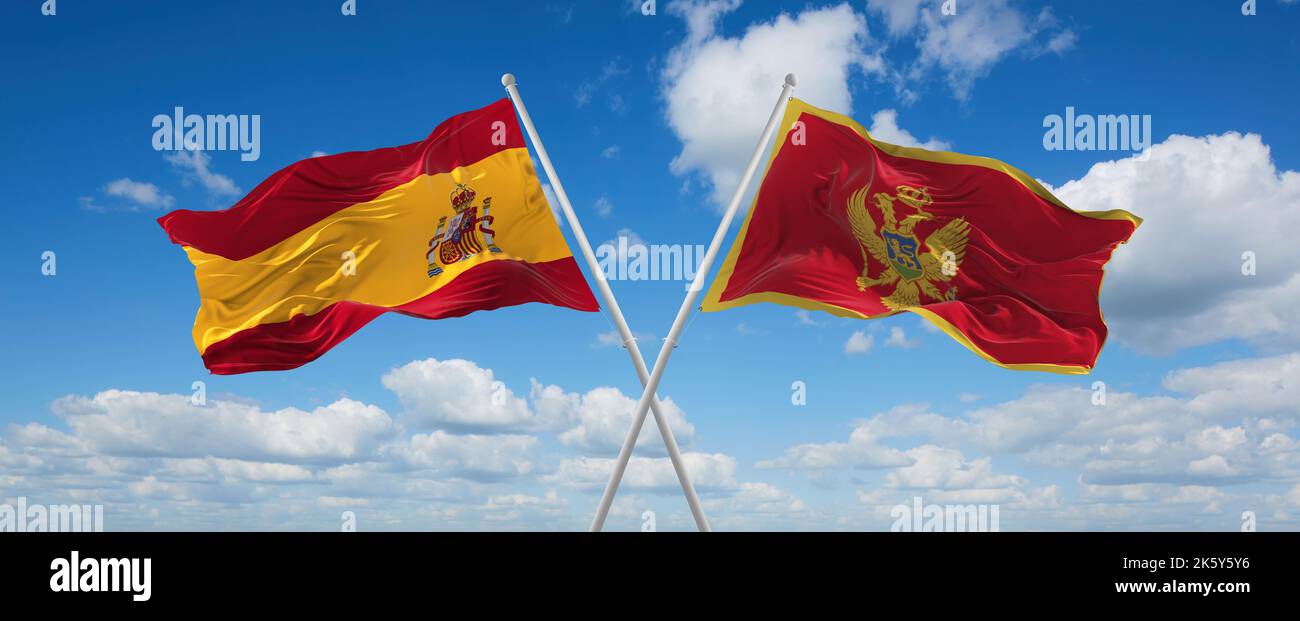 two crossed flags Montenegro and spain waving in wind at cloudy sky ...