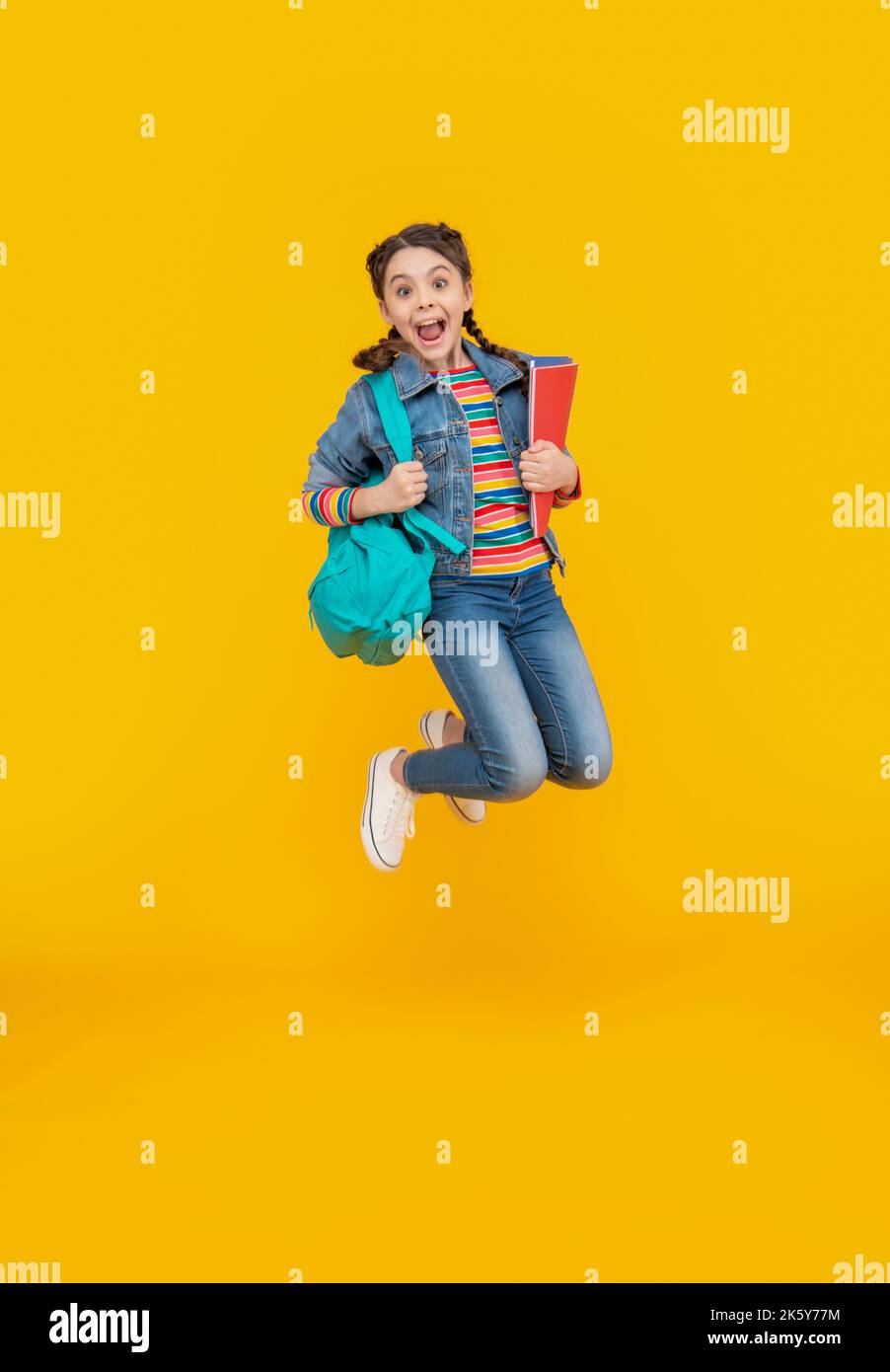 Excited schoolgirl screaming in midair, school. Energetic girl jumping ...