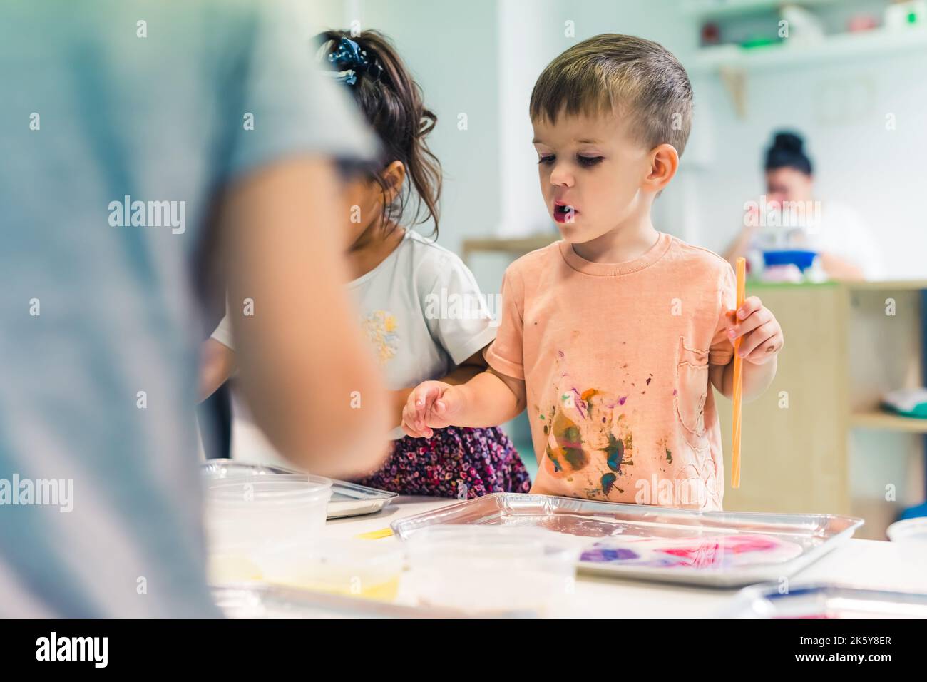 little Caucasian boy painting with his friends in the nursery, medium shot. High quality photo ...