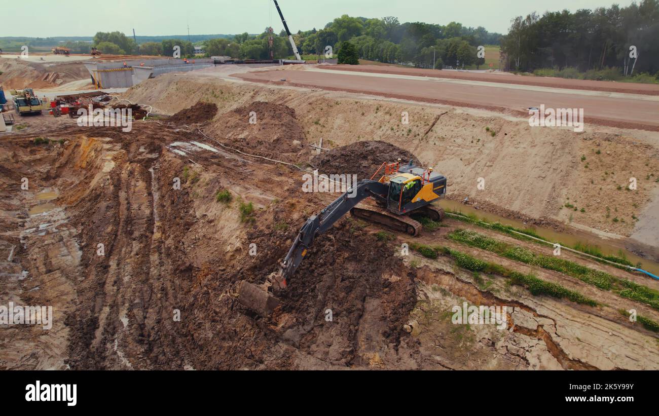 Long-reach crawler excavator moving earth at a construction site, digging the trenches for ...