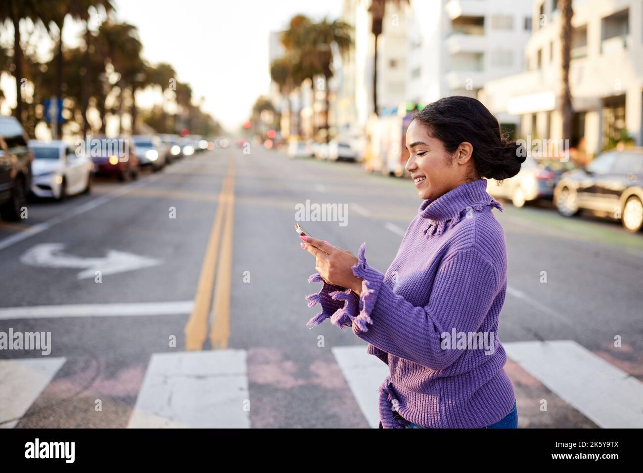 Happy woman using smart phone while crossing road Stock Photo - Alamy